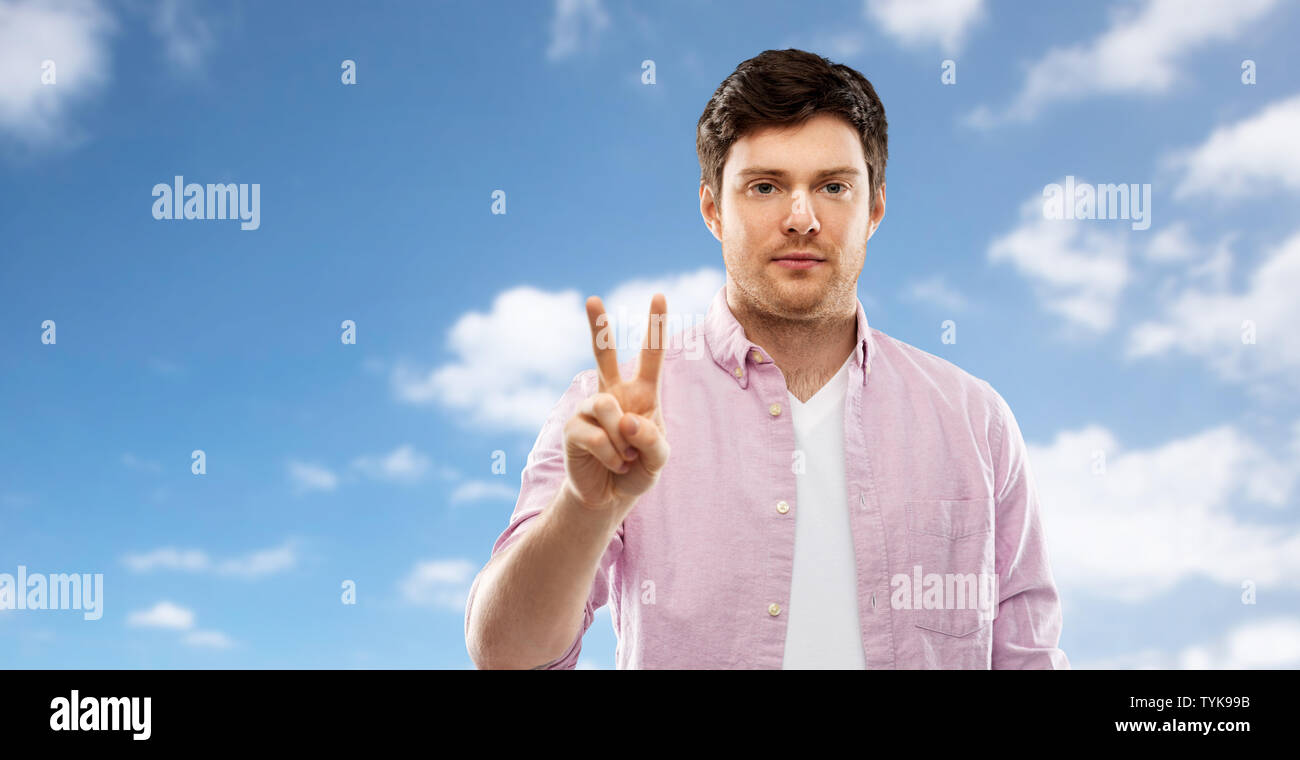 young man showing two fingers over sky Stock Photo - Alamy
