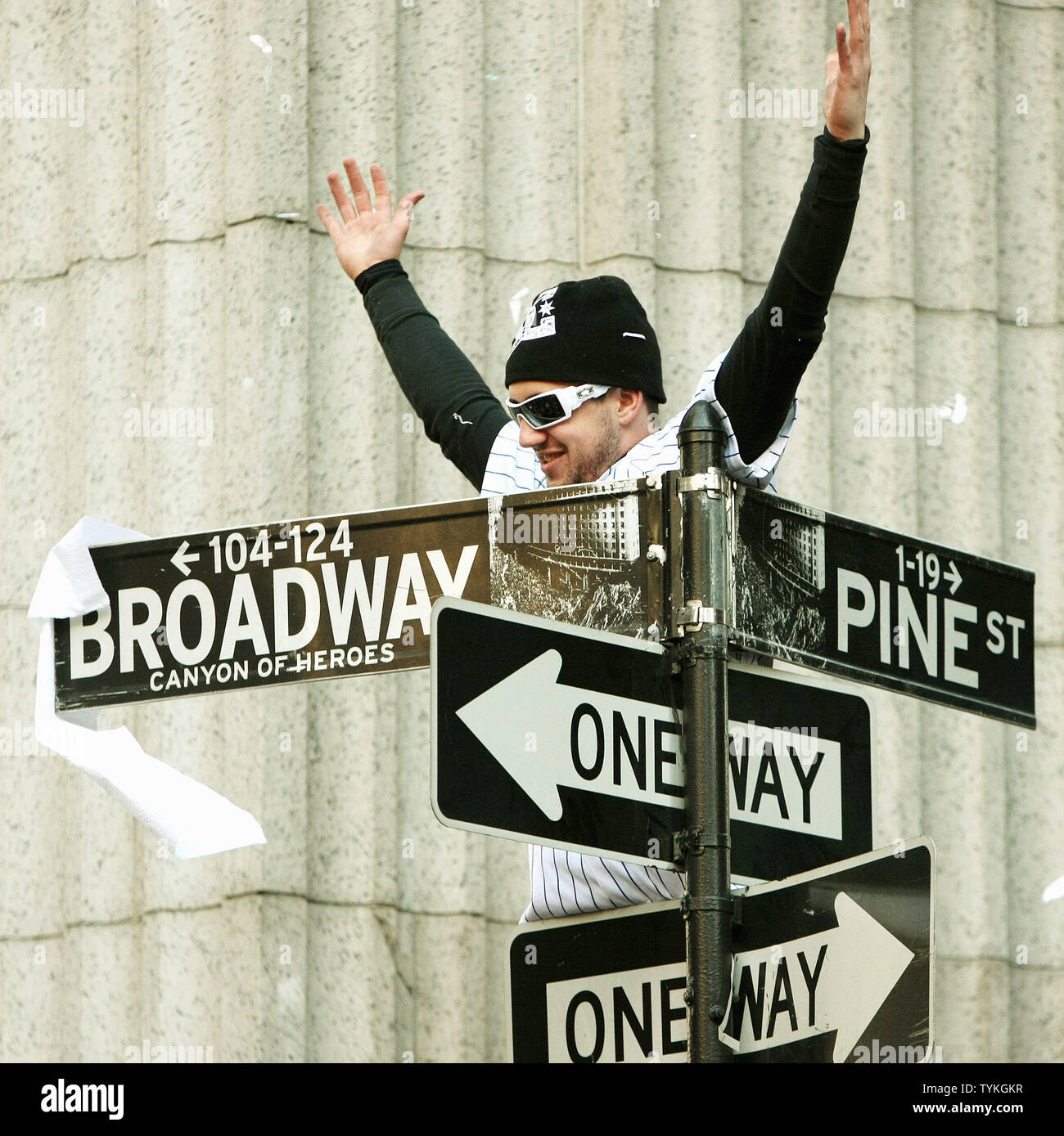 A man stands on a sign post to get a good view of the ticker-tape ...