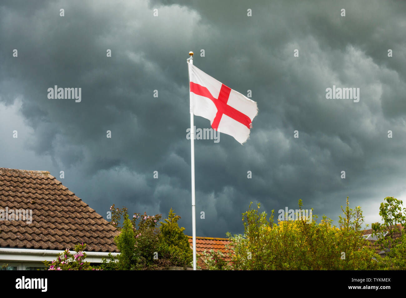 English flag of St George’s Cross on top of a flagpole, next to a house ...