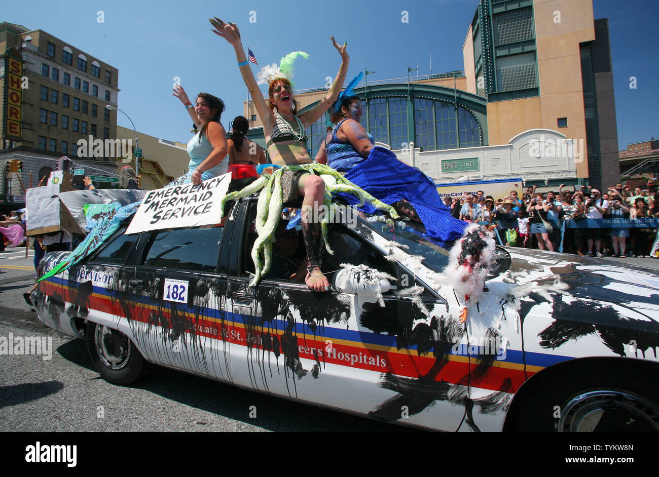People dressed as mermaids ride on a vehicle made to look like it's ...