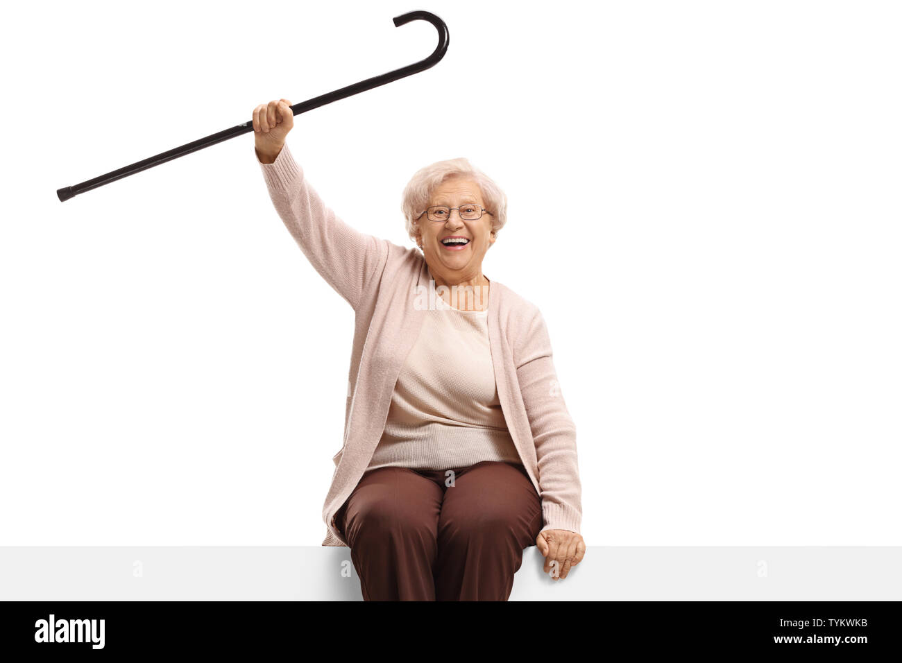 Happy senior woman with a cane sitting on a panel isolated on white ...
