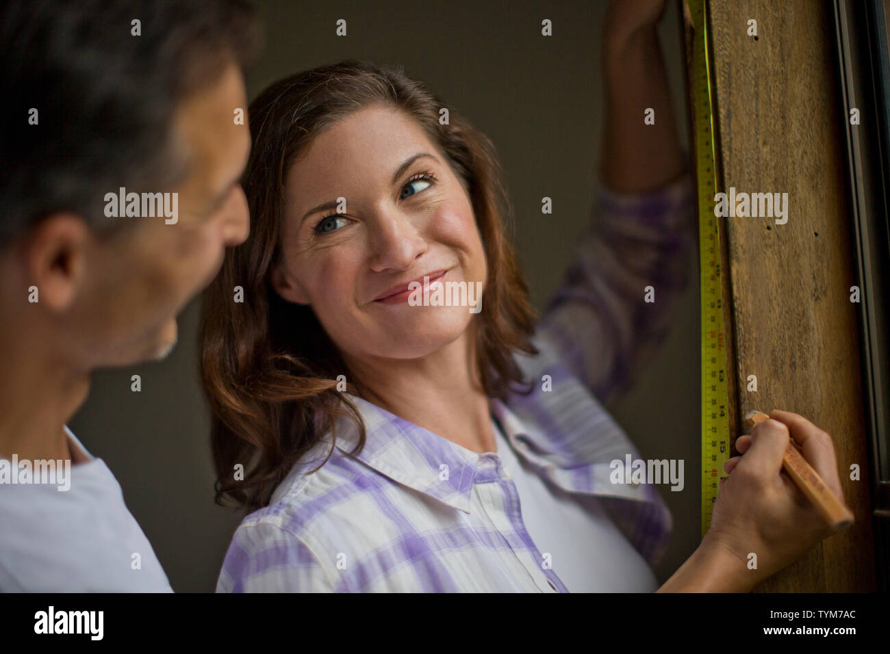Young woman takes a break from measuring the window sill to smile ...