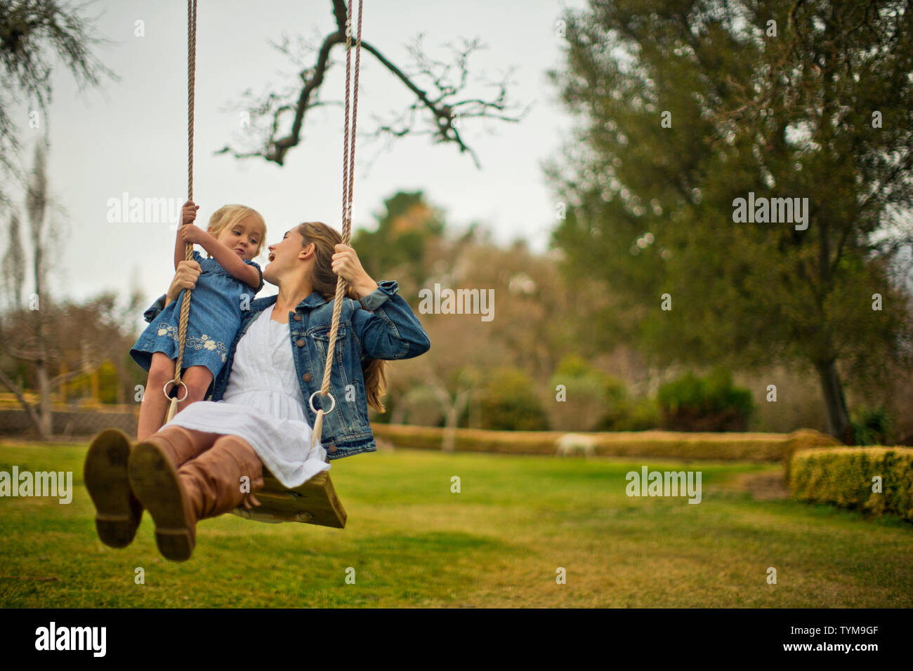Mother and daughter swinging on a wooden swing Stock Photo - Alamy