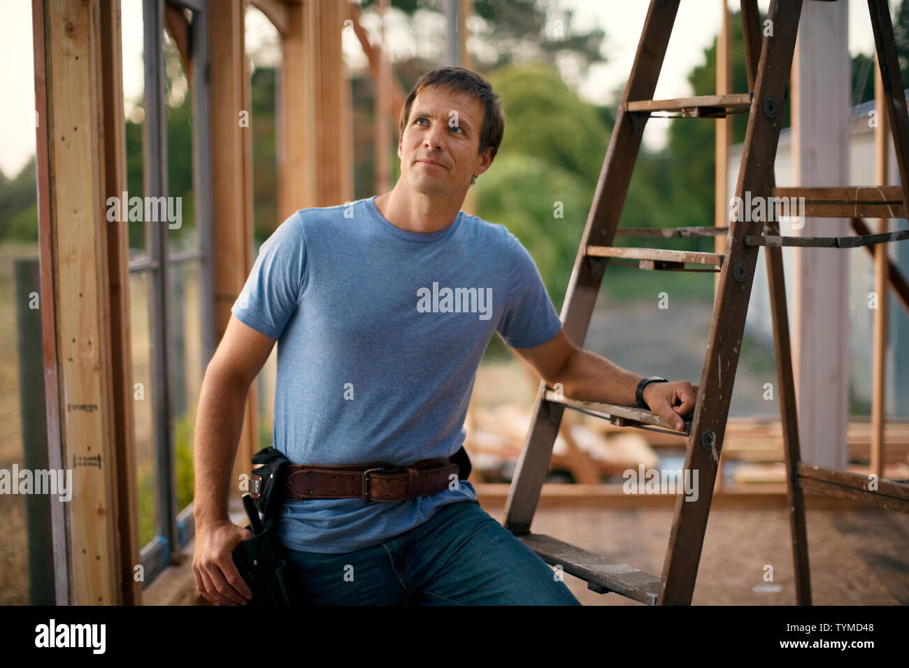 Builder on a construction site leaning against a ladder Stock Photo - Alamy