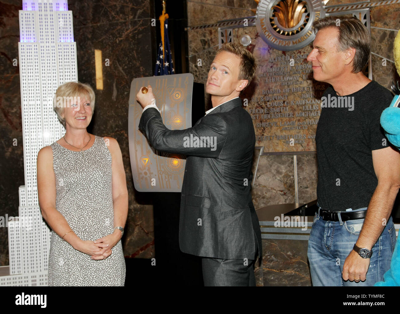 Neil Patrick Harris, center, throws a switch which lights a model of ...