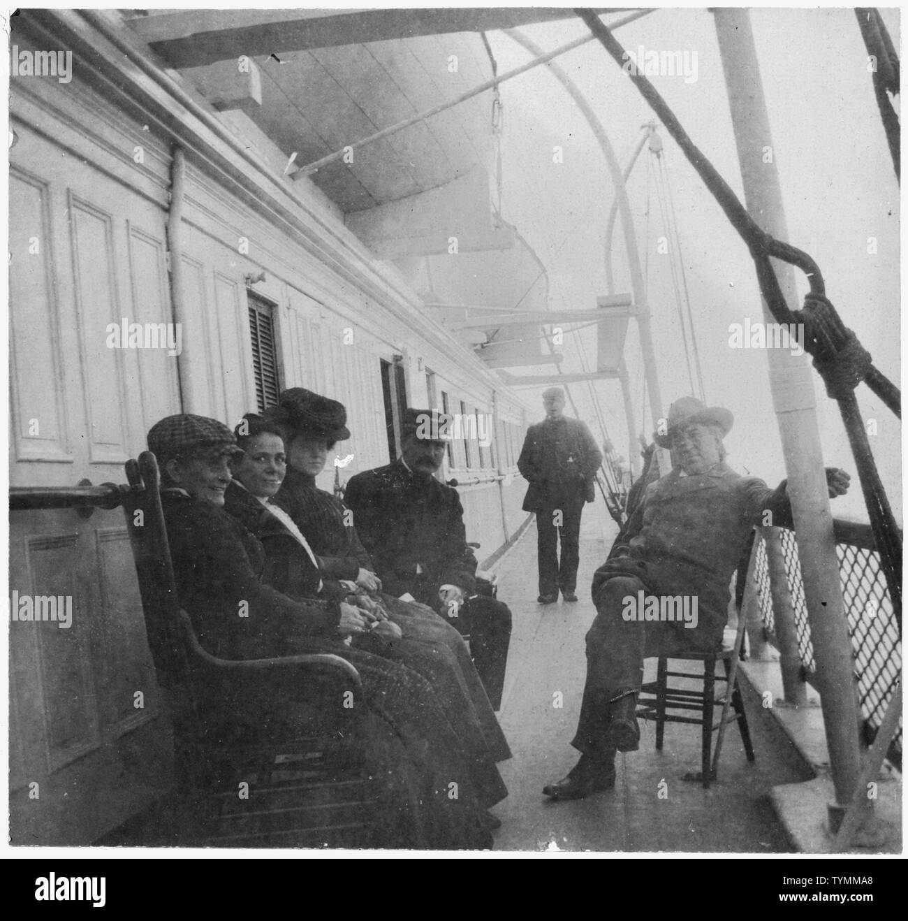 Three men, three women on ship's deck. Man on the far right is ...