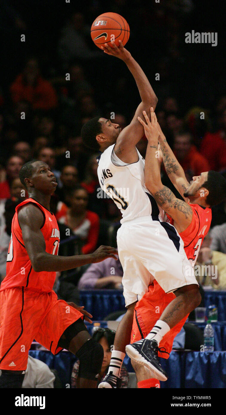 Eric Atkins of Notre Dame, center, goes to shoot as Louisville's Peyton ...