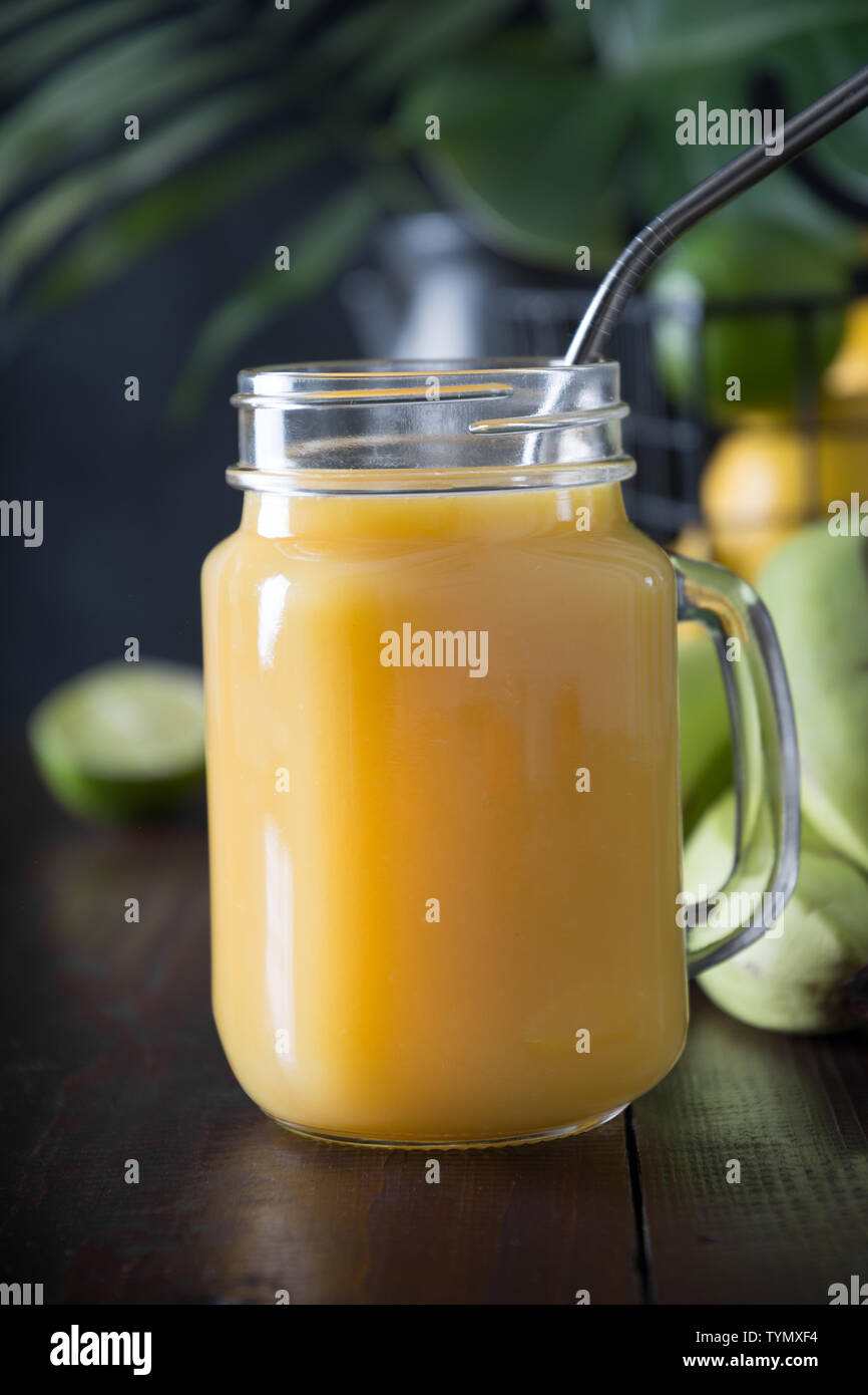 Fresh summer fruits smoothies or juice with banana, lime on dark ...