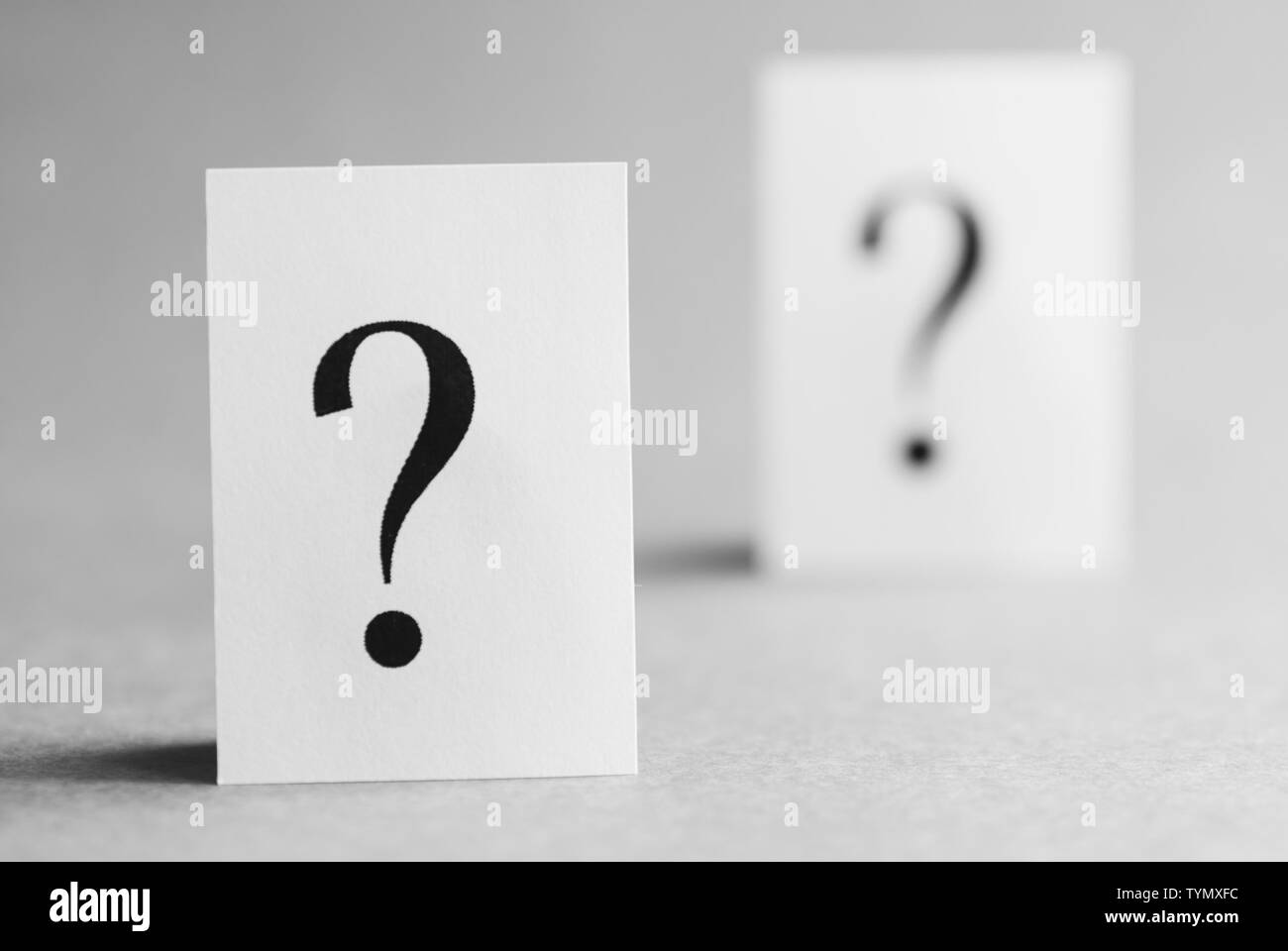 Two question marks printed onto white cards placed to the side one ...