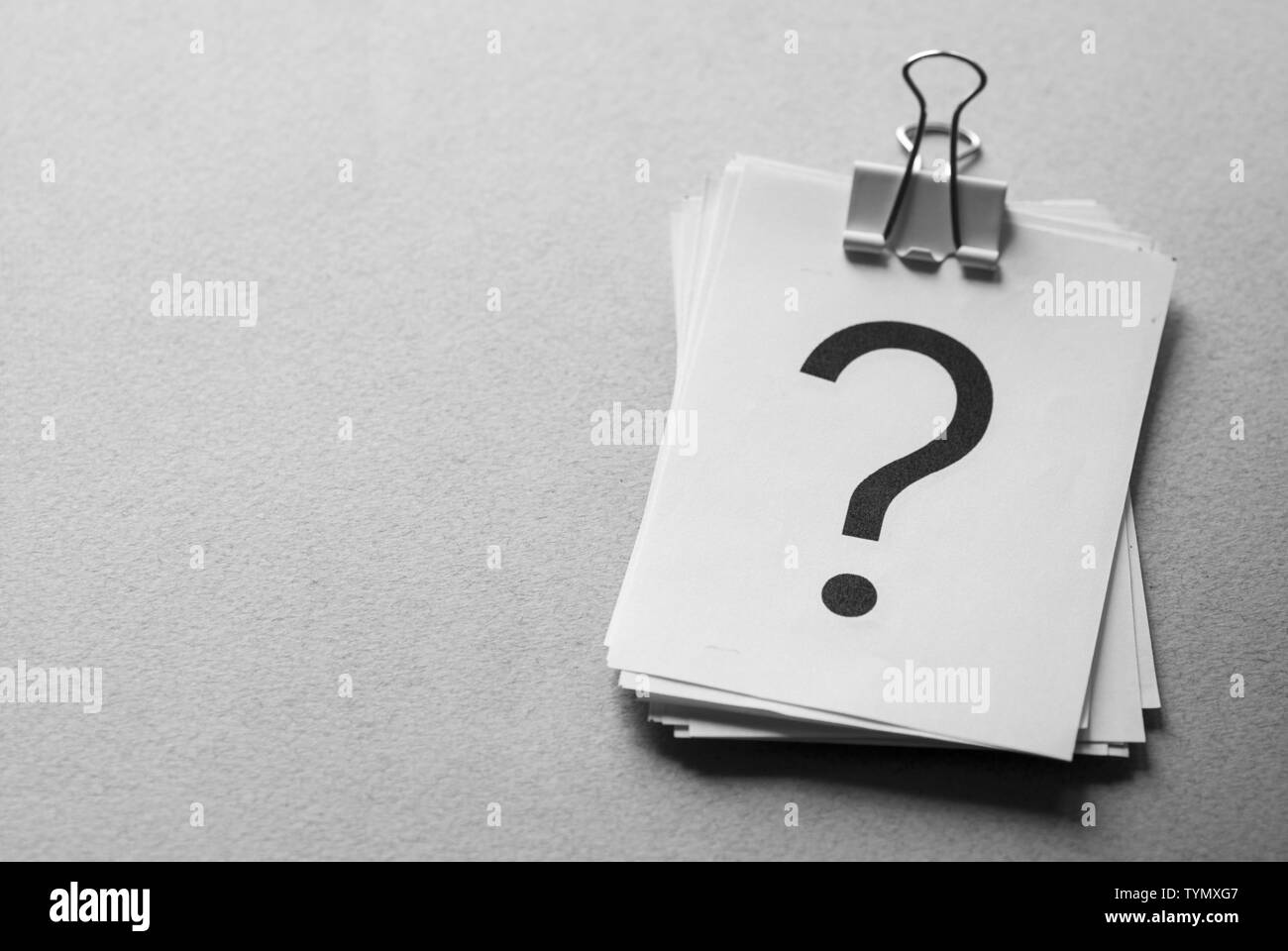 Stack of white cards printed with question marks held together with a ...