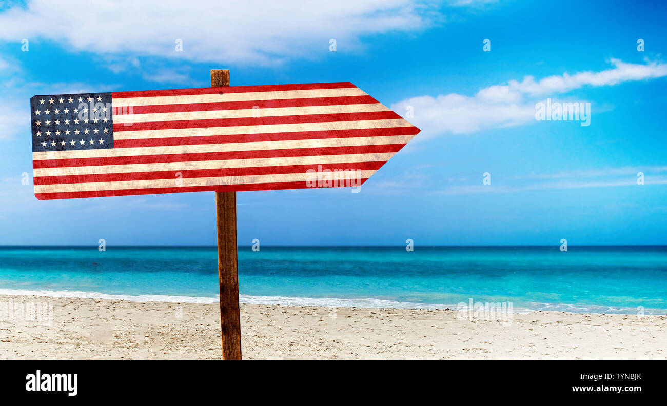 USA flag on wooden table sign on beach background. There is beach and ...