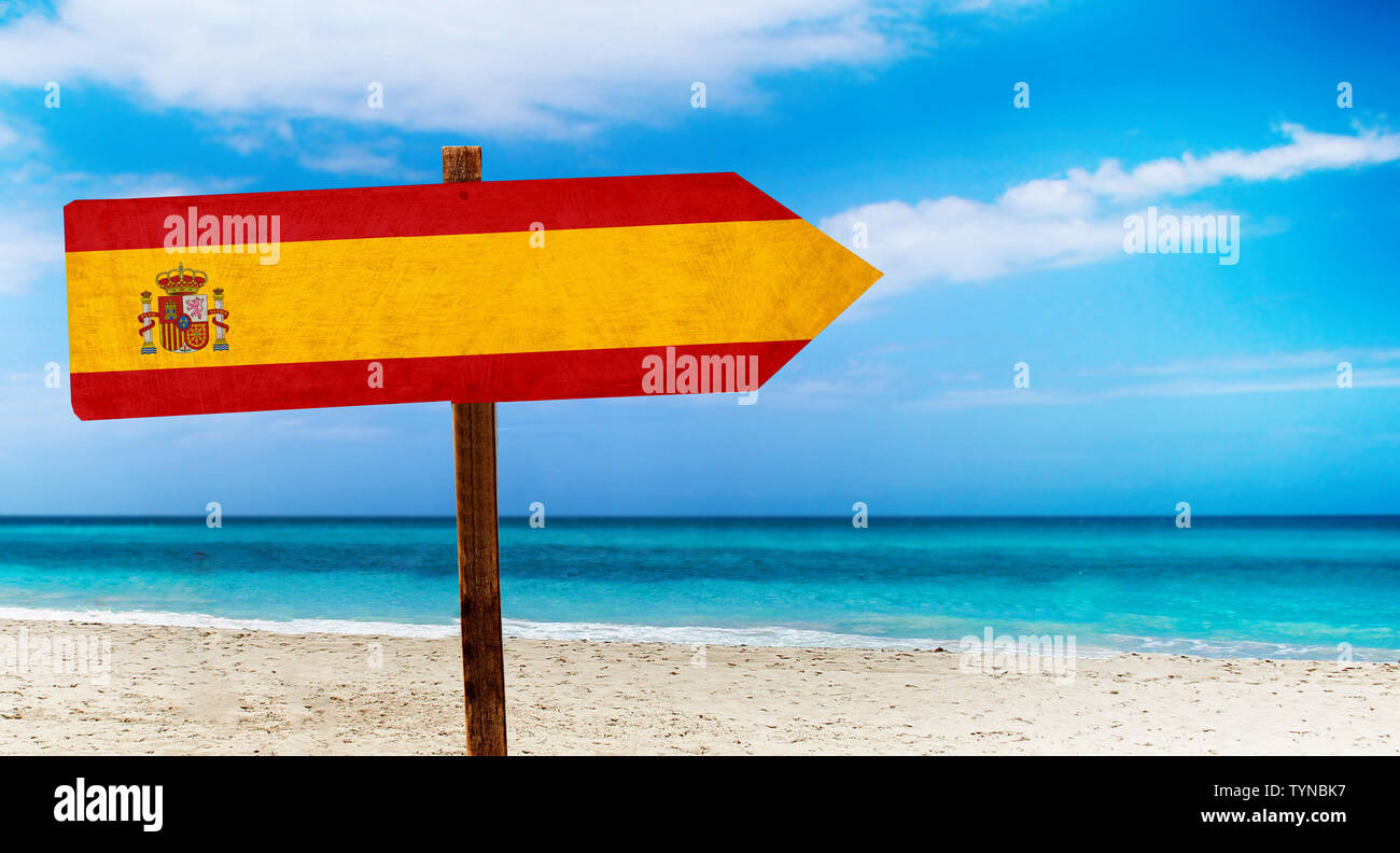 Spain flag on wooden table sign on beach background. There is beach and ...