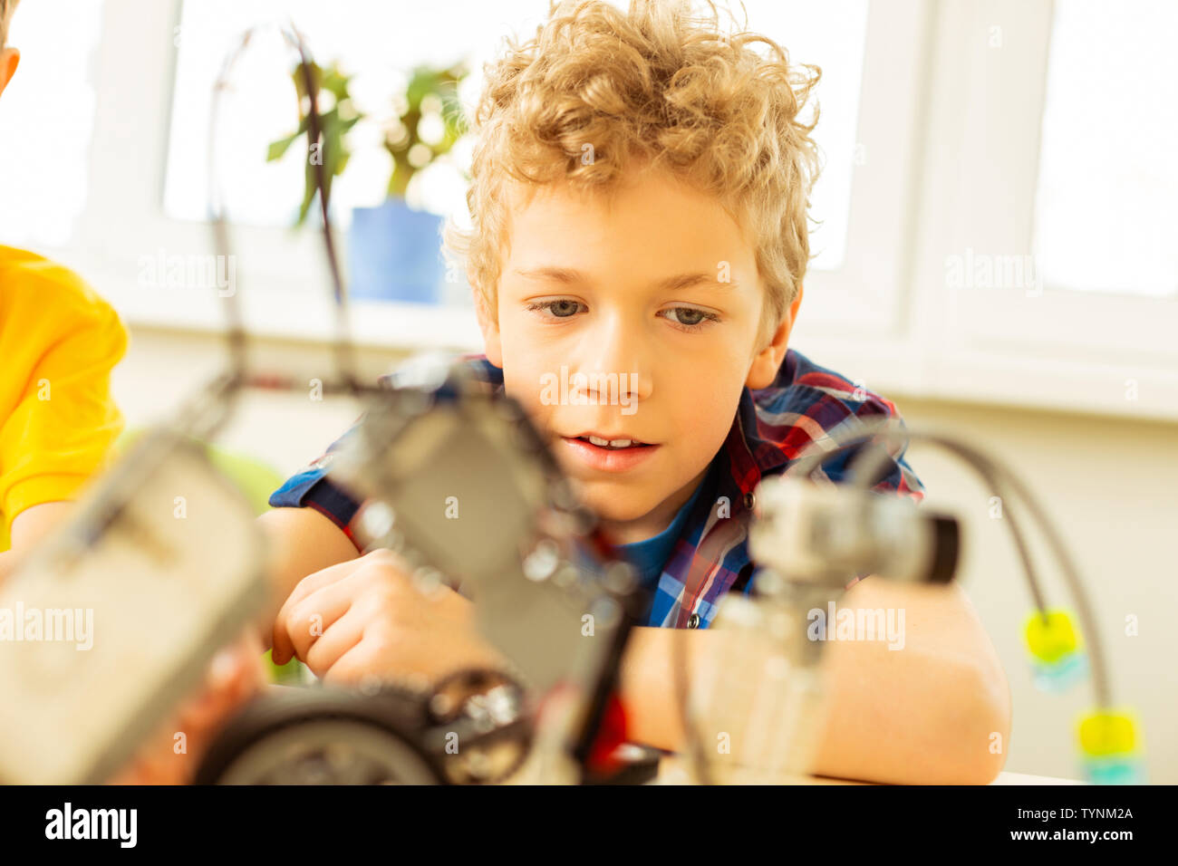 School boy. Face of a smart young blonde boy while looking at his robot ...