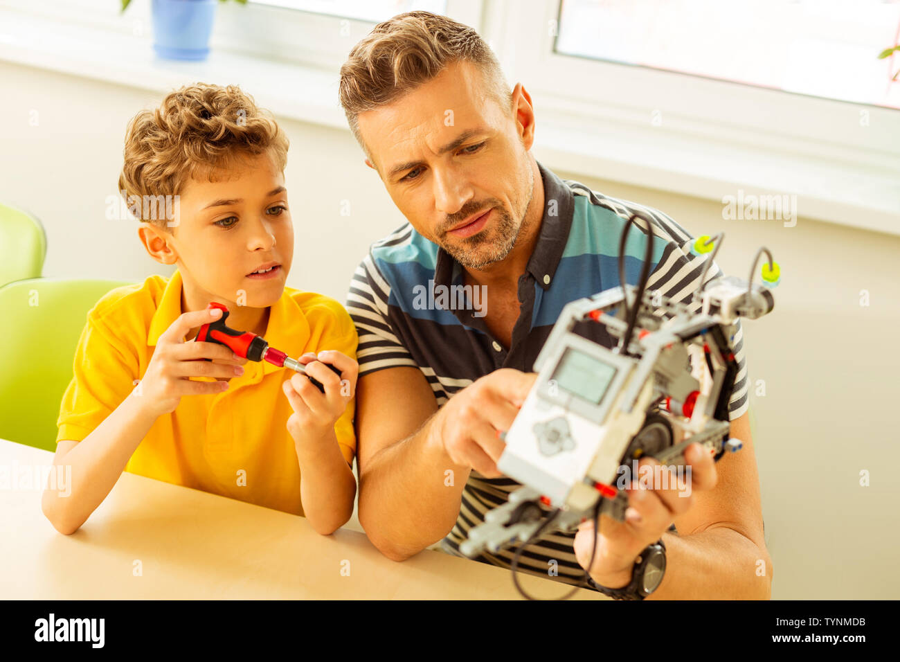 How to fix it. Nice thoughtful man looking at the robot while thinking ...