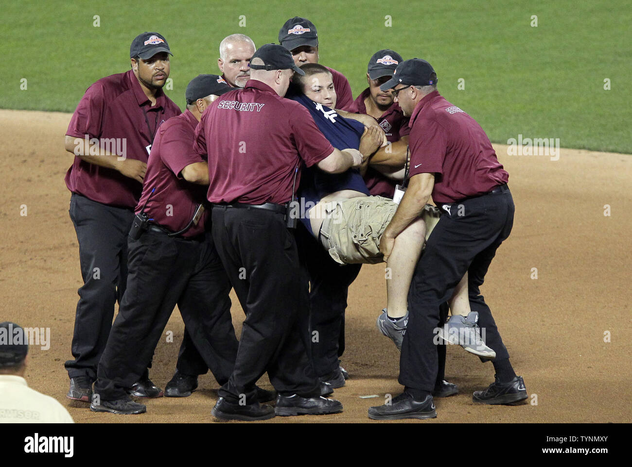 A group of security guards carry a man off of the field who ran out on ...