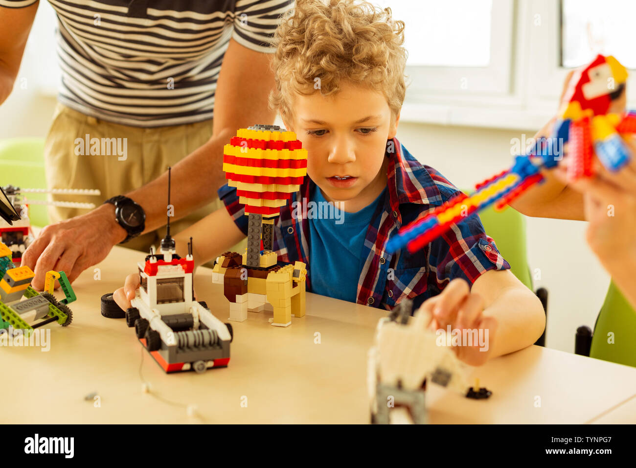 Creative activity. Cute blonde boy being busy with toys constructing ...