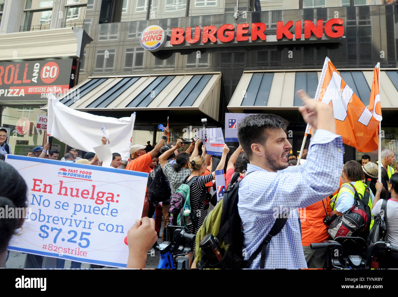 People hold up signs protesting the low wages for workers at fast food ...