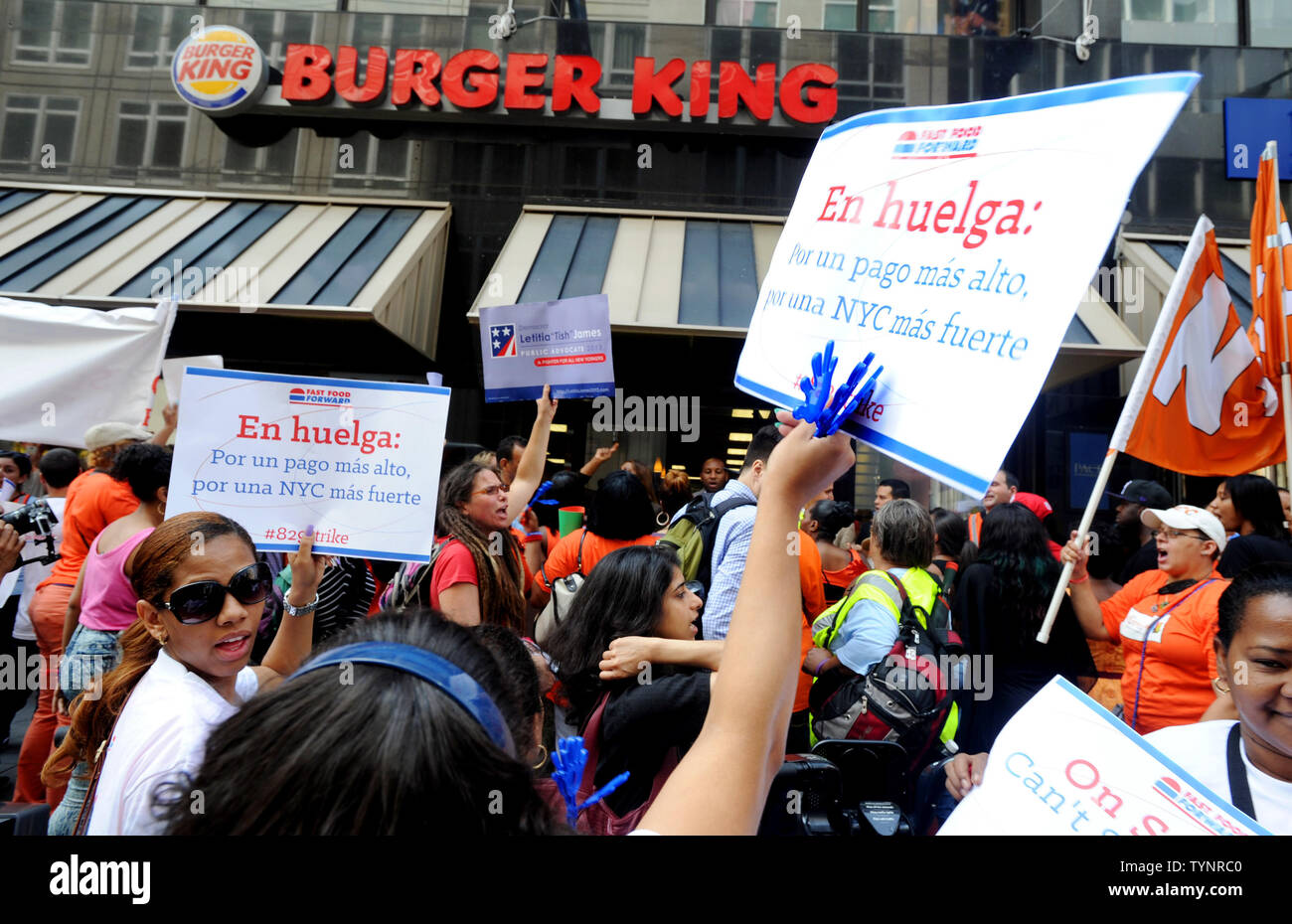 People hold up signs protesting the low wages for workers at fast food ...