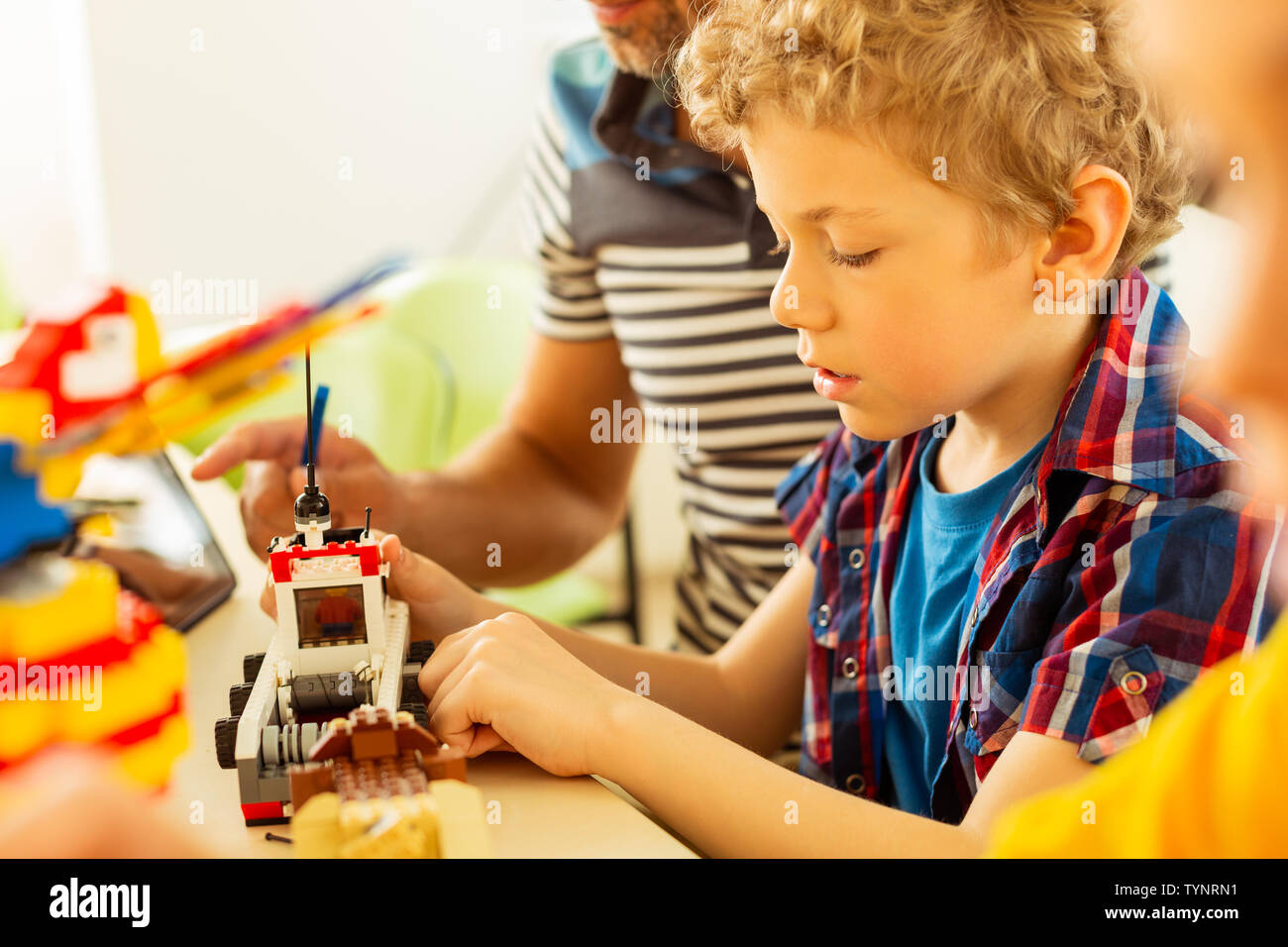 Being creative. Happy excited boy smiling while trying to construct ...