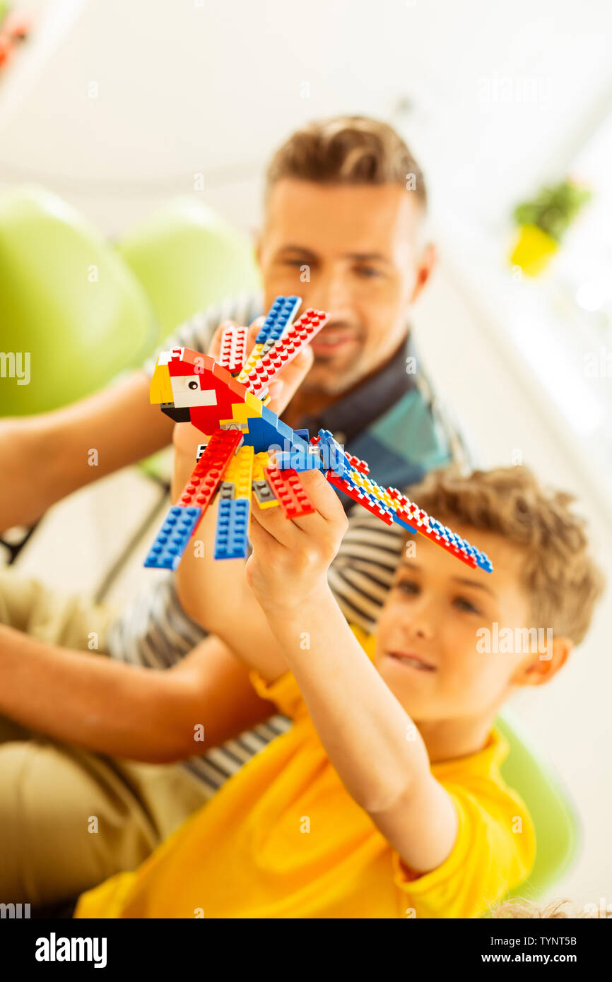 Favourite toy. Happy cute boy playing with a toy parrot while ...