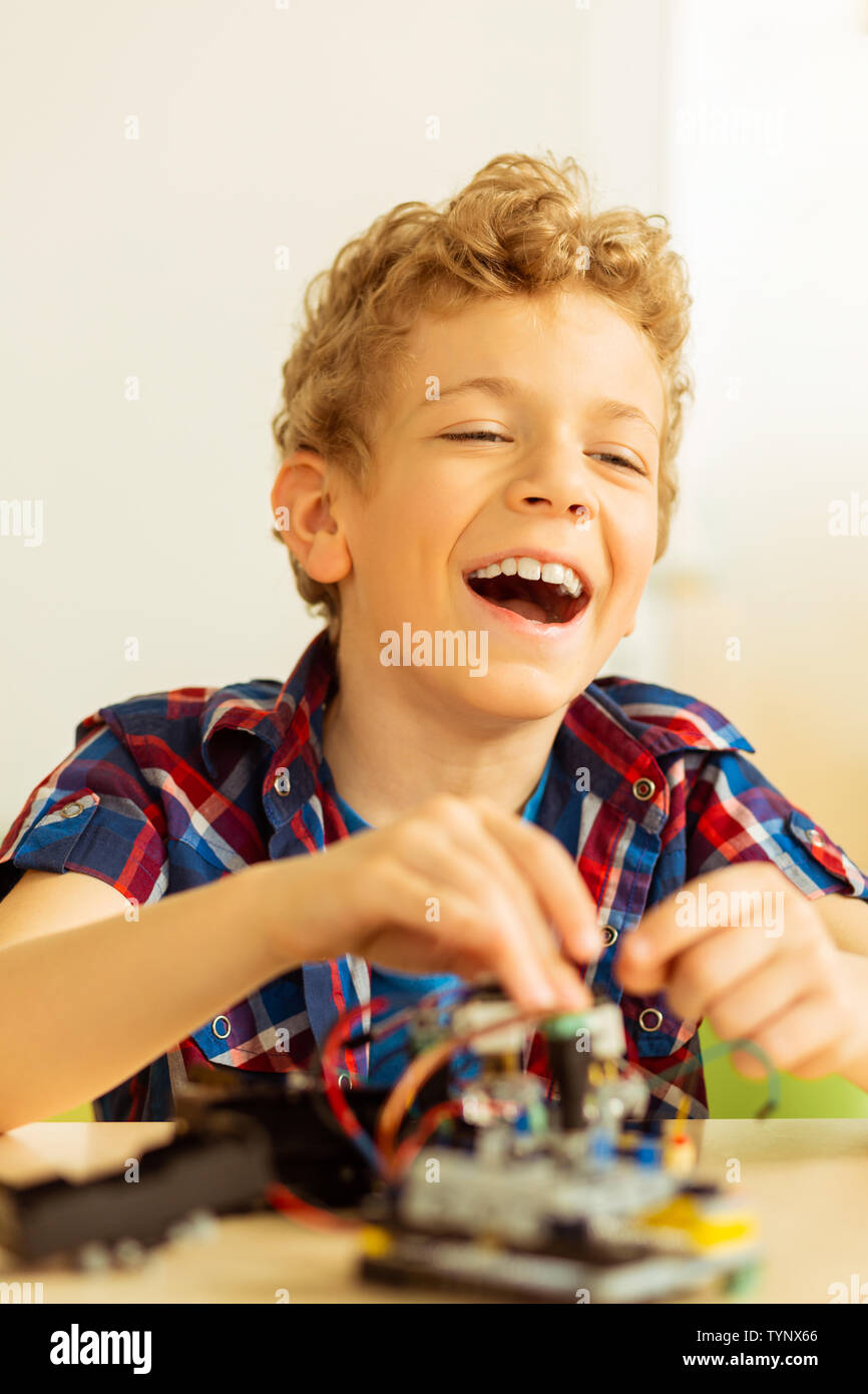 Interesting science. Joyful happy boy trying to construct his own robot ...