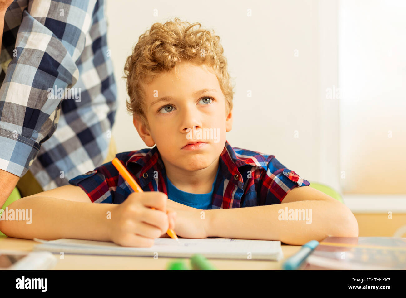 During the lesson. Serious blonde boy being bored while writing his ...