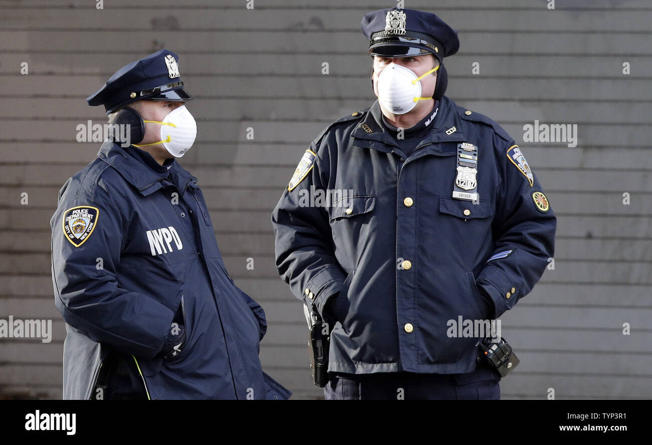 NYPD police officers wear surgical masks at the scene of 2 collapsed ...