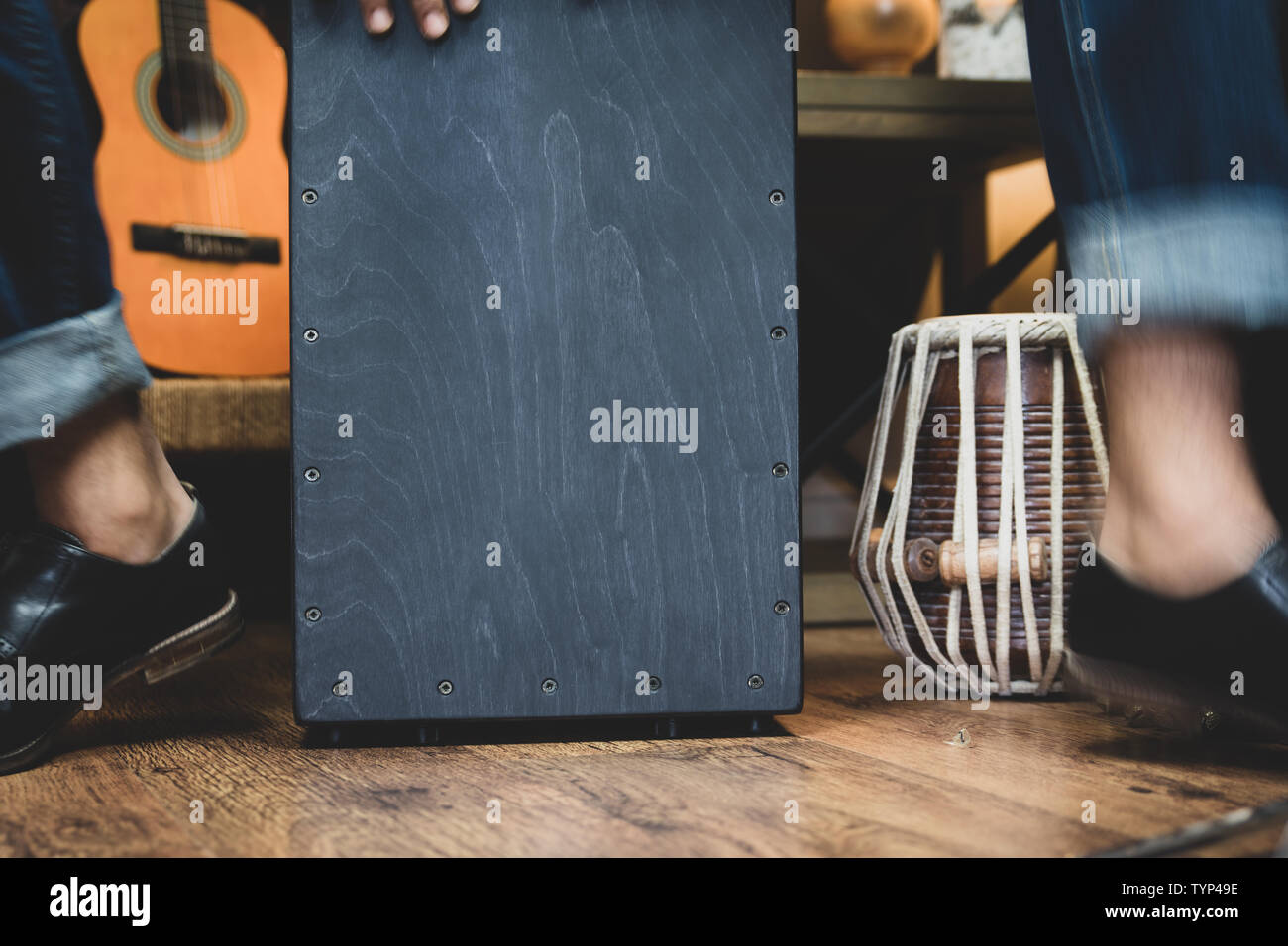 Man in double monk shoes playing the Peruvian percussion instrument ...