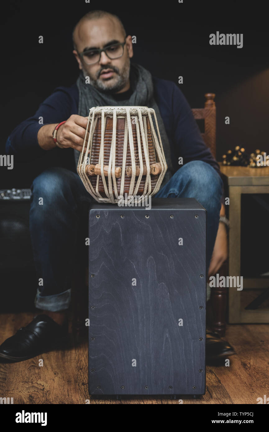 Indian ethnicity man playing the tabla and cajon, percussion ...