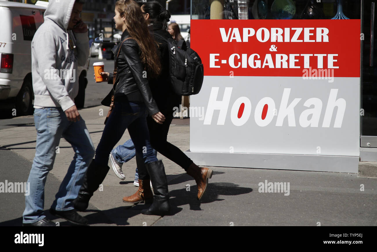People walk by a store that sells E-Cigarettes and other tobacco ...