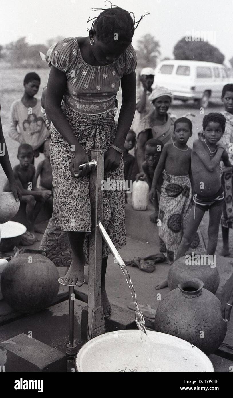 WOMAN PUMPING WATER FROM A WELL, WHILE OTHERS WATCH Stock Photo - Alamy