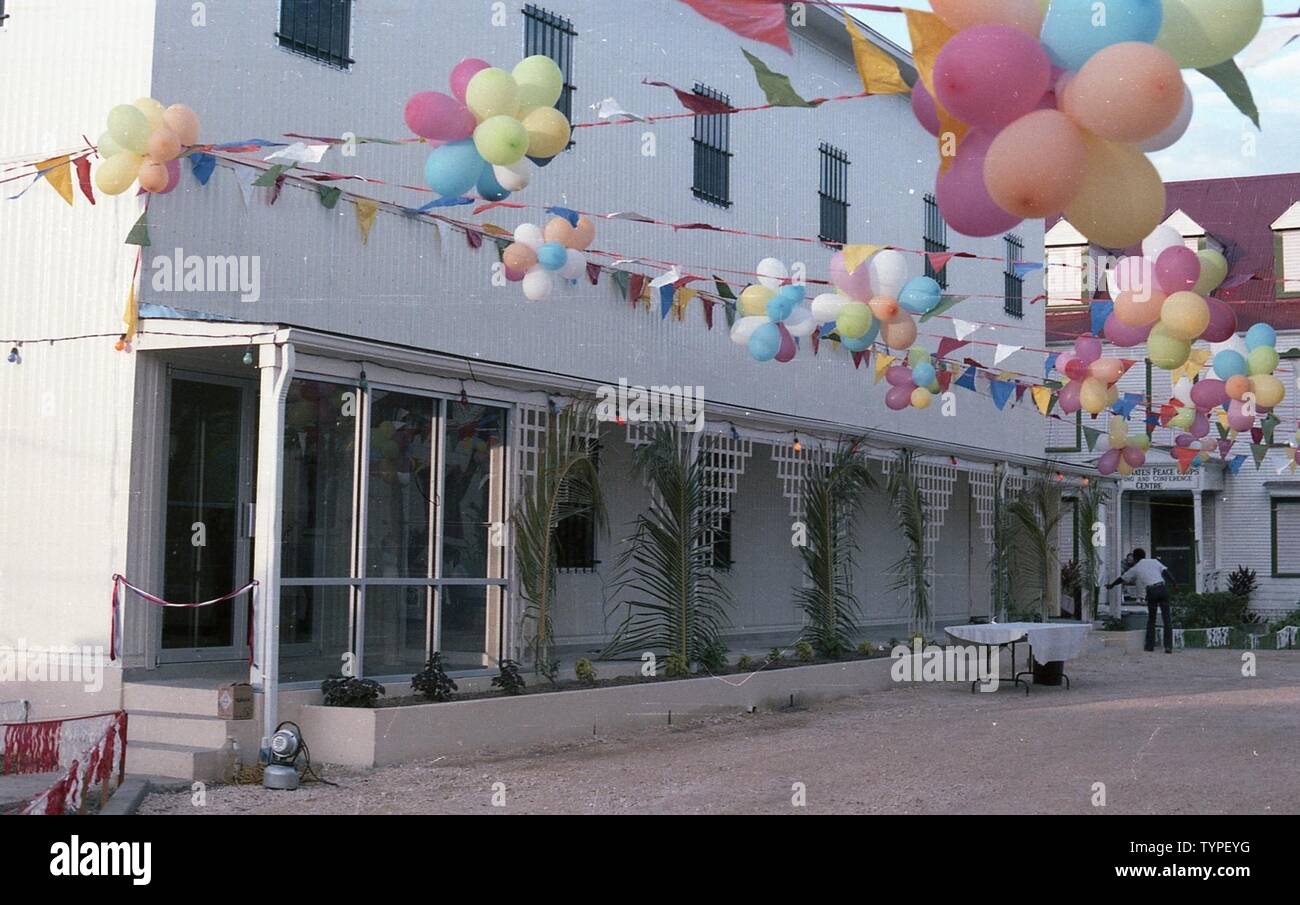 DECORATIONS OUTSIDE BUILDING WITH PALM TREES AND COVERED TABLE. SIGN ON ...
