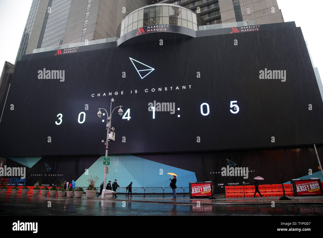 People walk by a giant new billboard that hangs below the Marriott ...