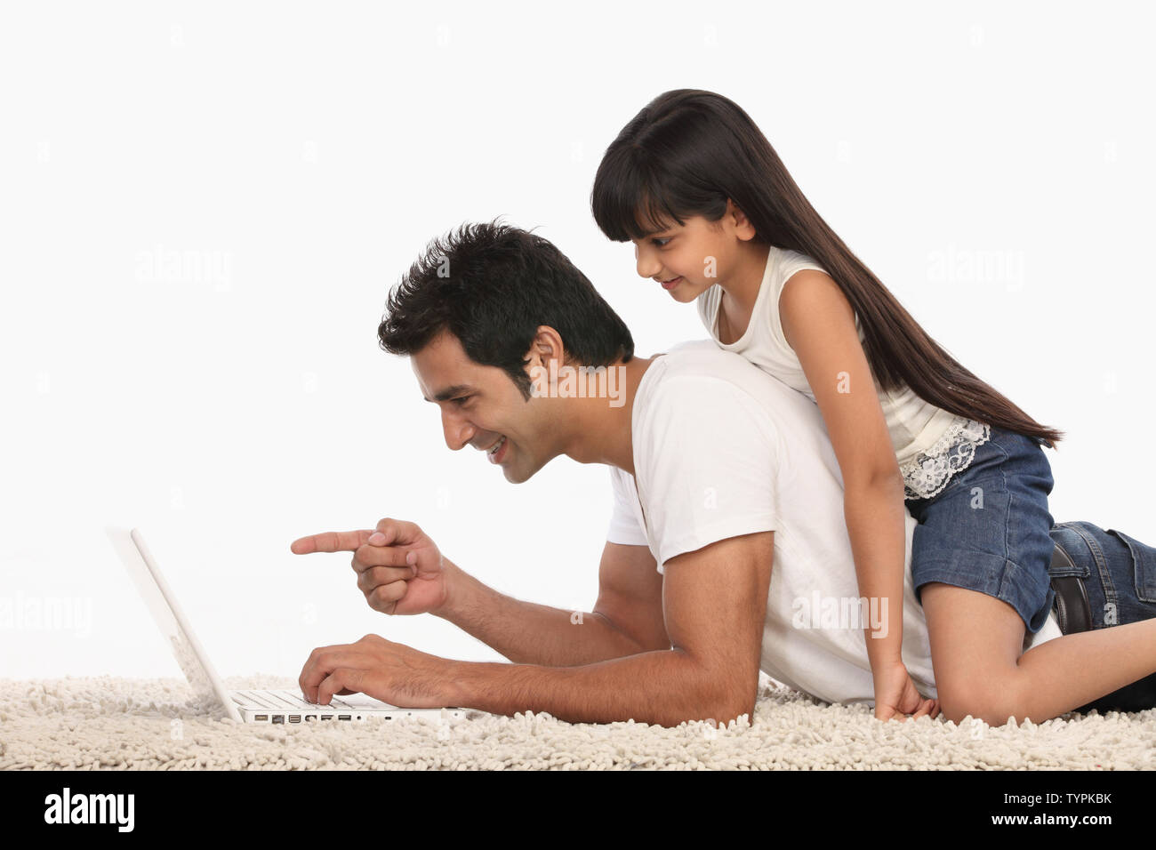 Man working on a laptop with his daughter smiling Stock Photo - Alamy