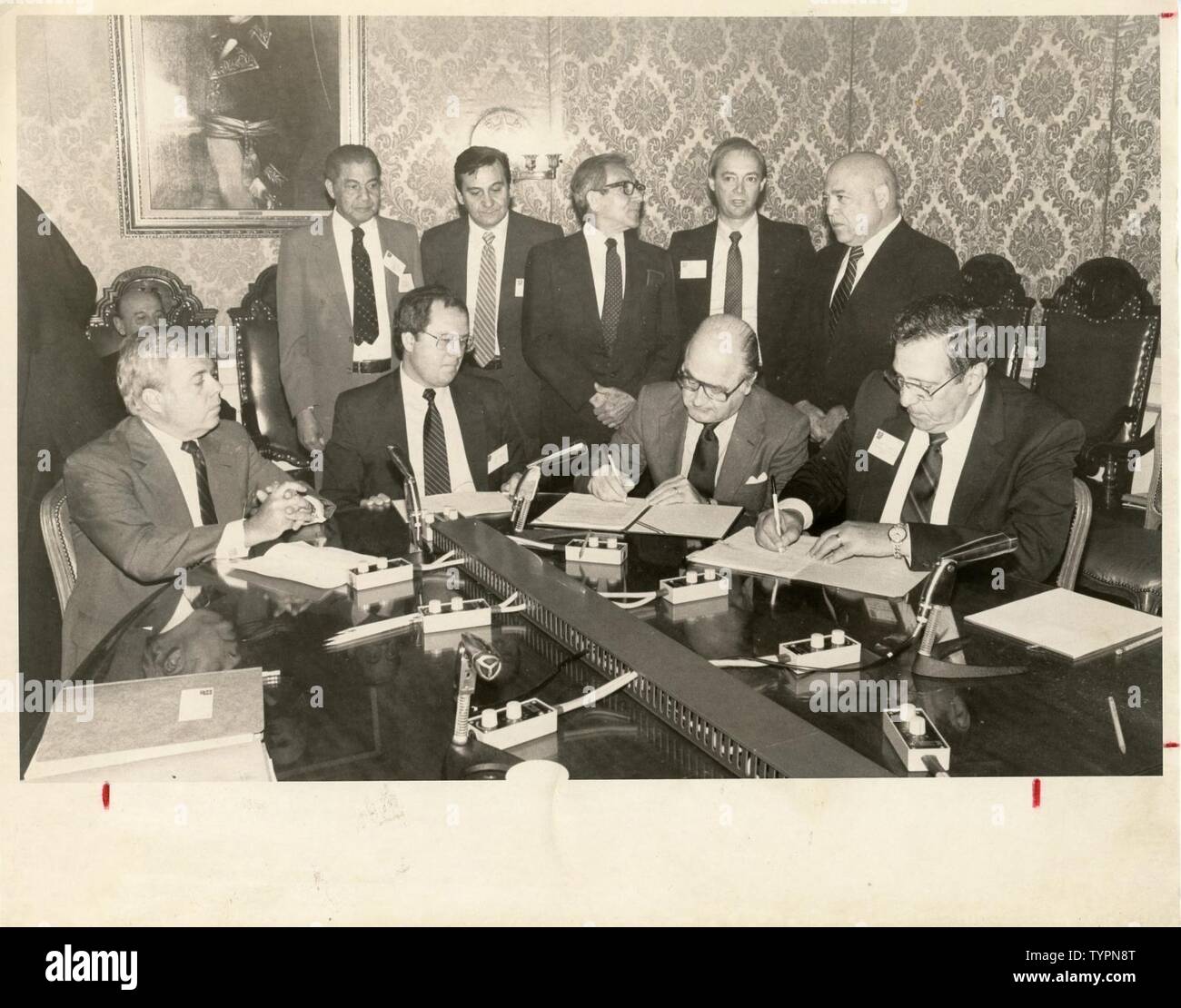GROUP OF MEN SIGNING PAPERS AT TABLE. MEN STANDING UP OBSERVING Stock ...