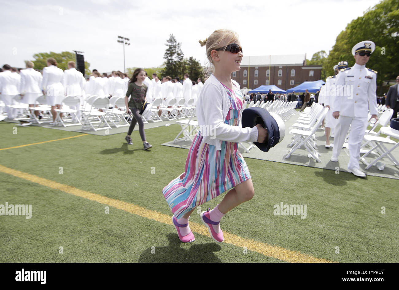 A girl runs with a graduates hat that she picked up off of the ground ...