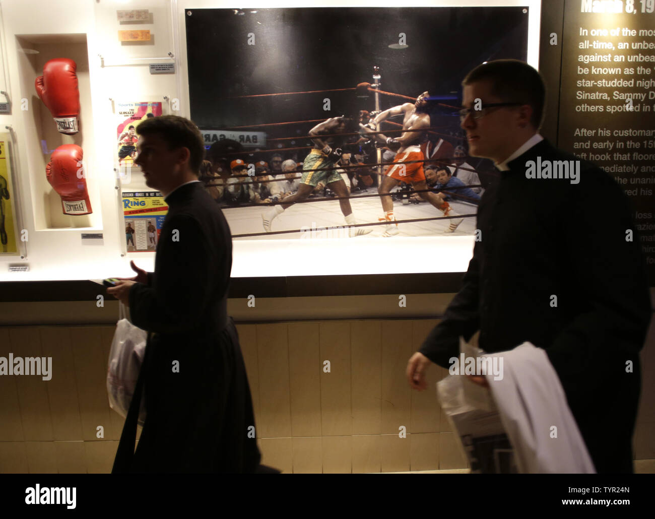 Two priests walk by a photo of boxing great Muhammad Ali in the hall ...