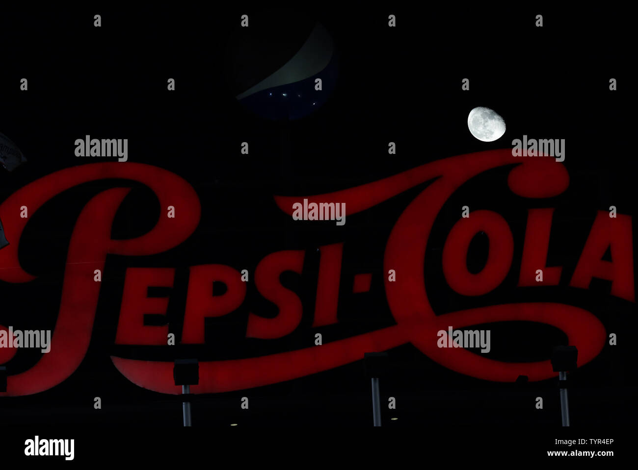 An almost full moon rises above a Pepsi-Cola sign when the New York ...