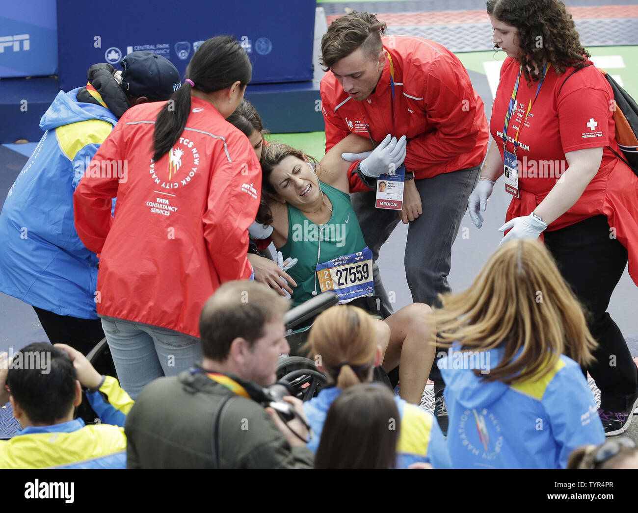 A runner is helped as she collapses at the finish line at the NYRR TCS ...