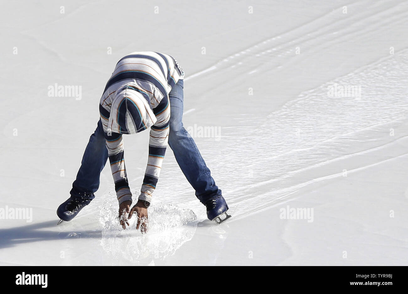 A man reaches down to touch the melting ice water while he skates in ...