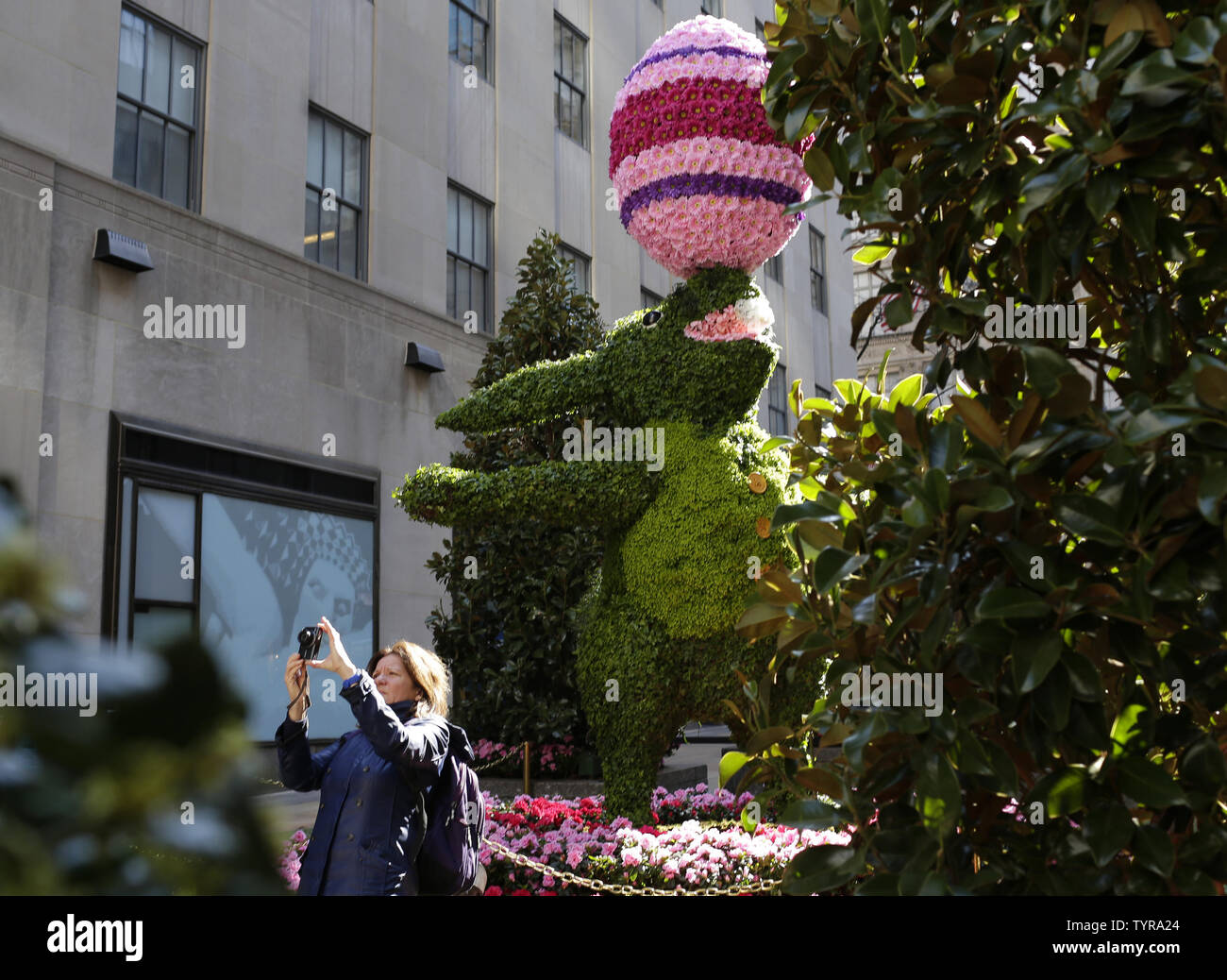 A woman takes a selfie near an Easter bunny topiary made of moss and ...