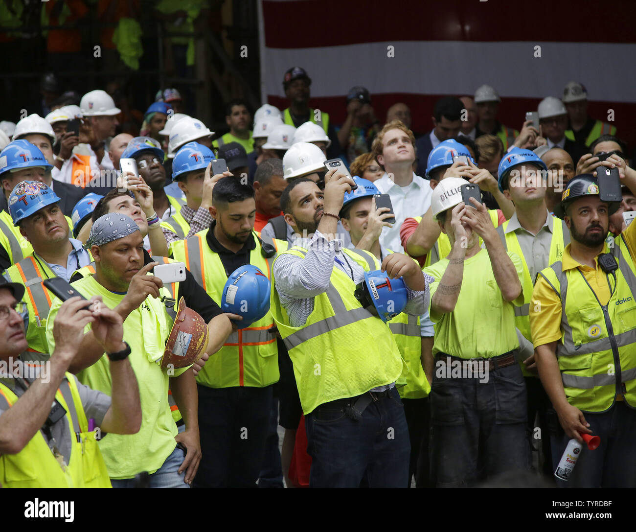 Construction workers watch the last concrete bucket with an American ...