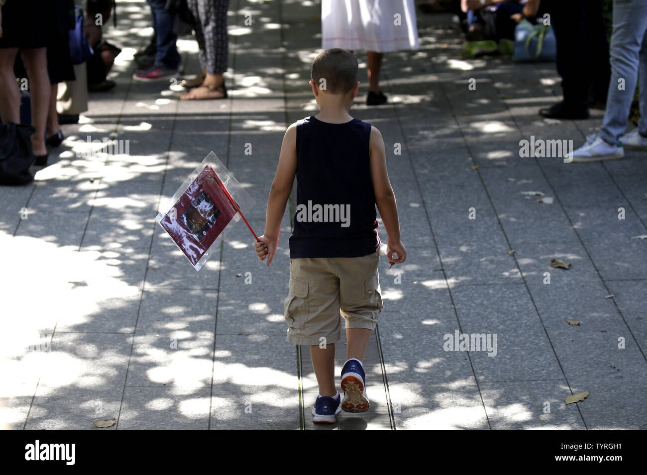 A boy holds a photo of the Twin Towers near the Reflecting Pools at the ...