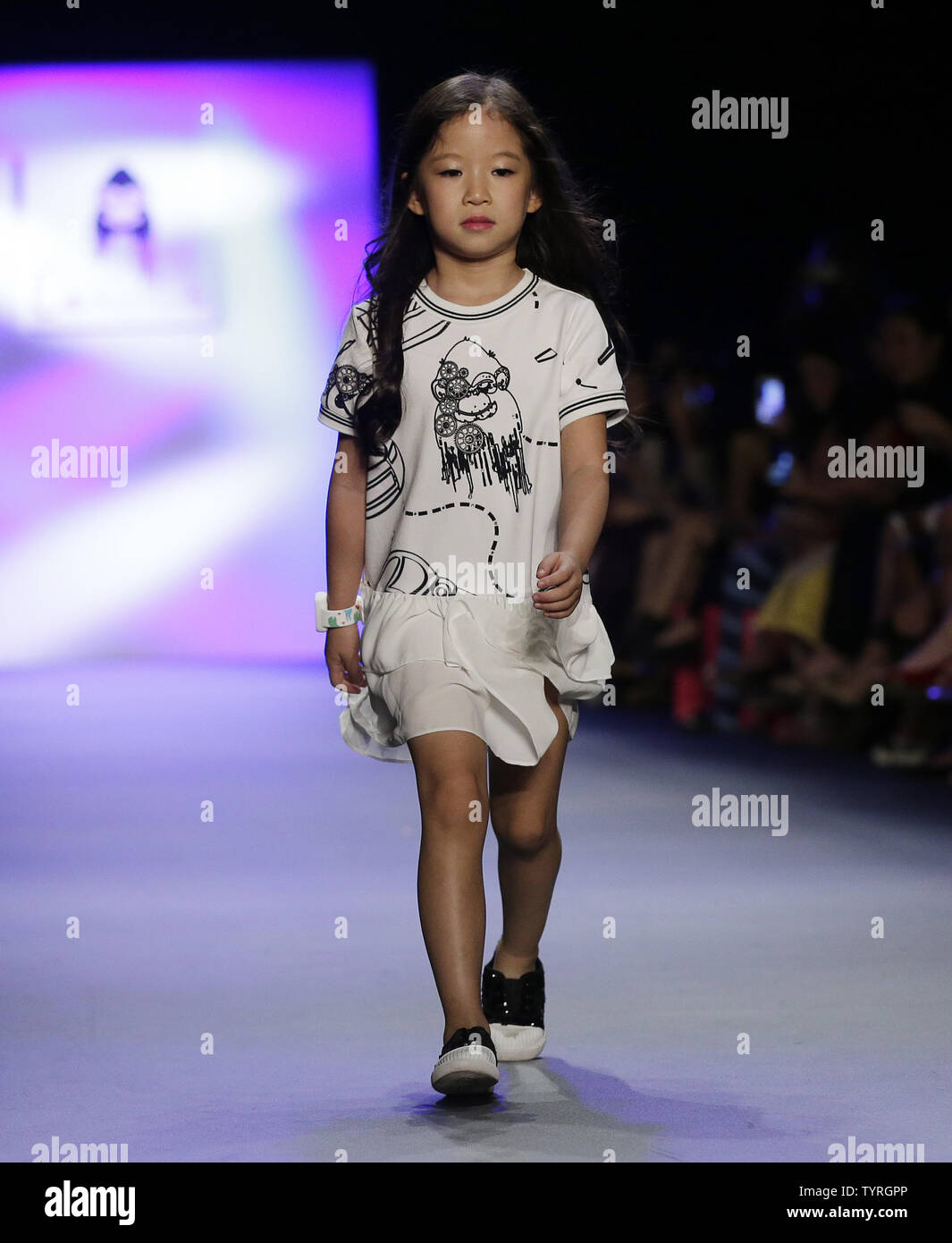 A child model walks on the runway at the Comme Tu Es fashion show ...