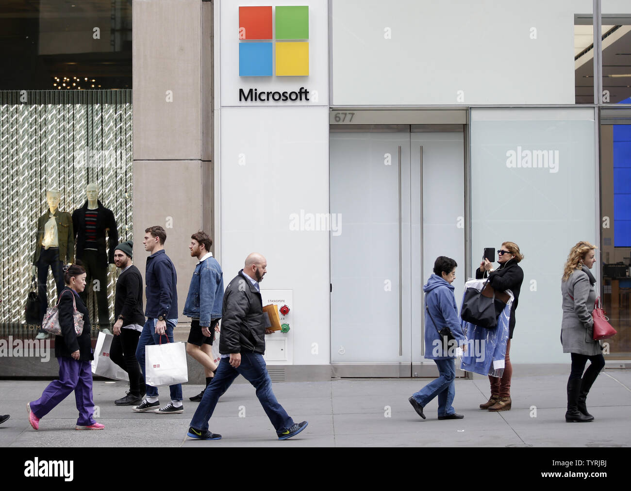 Pedestrians walk by the Brand logo for Microsoft at the Microsoft Store ...