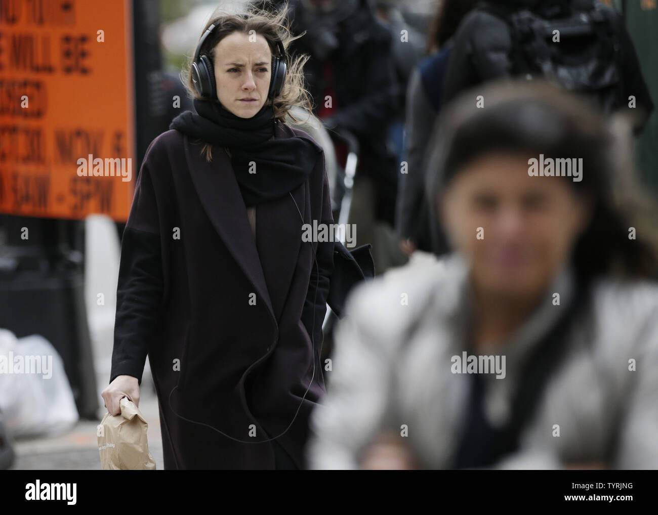 A woman walks on the sidewalks of Manhattan wearing headphones on a ...