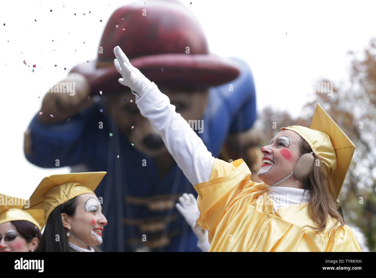 A clown throws confetti on a crowd revelers as she moves down the ...