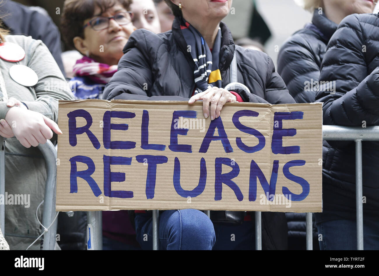 Protesters hold up signs as they participate in a Tax March protest in ...
