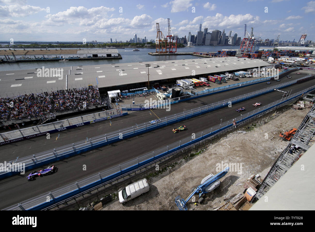 Competing cars race around the track with the Manhattan skyline and One ...