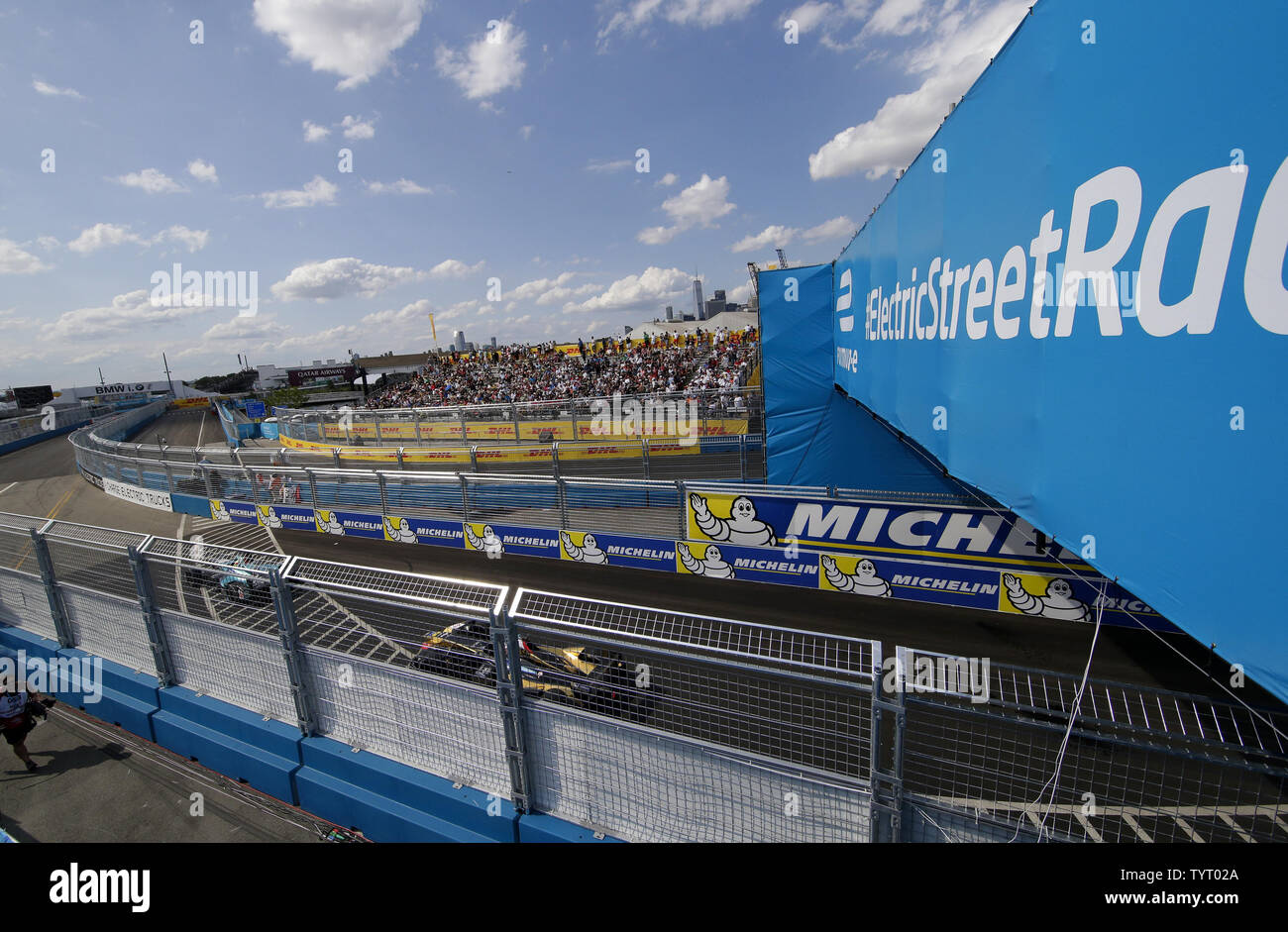 Competing cars race around the track with the Manhattan skyline and One ...